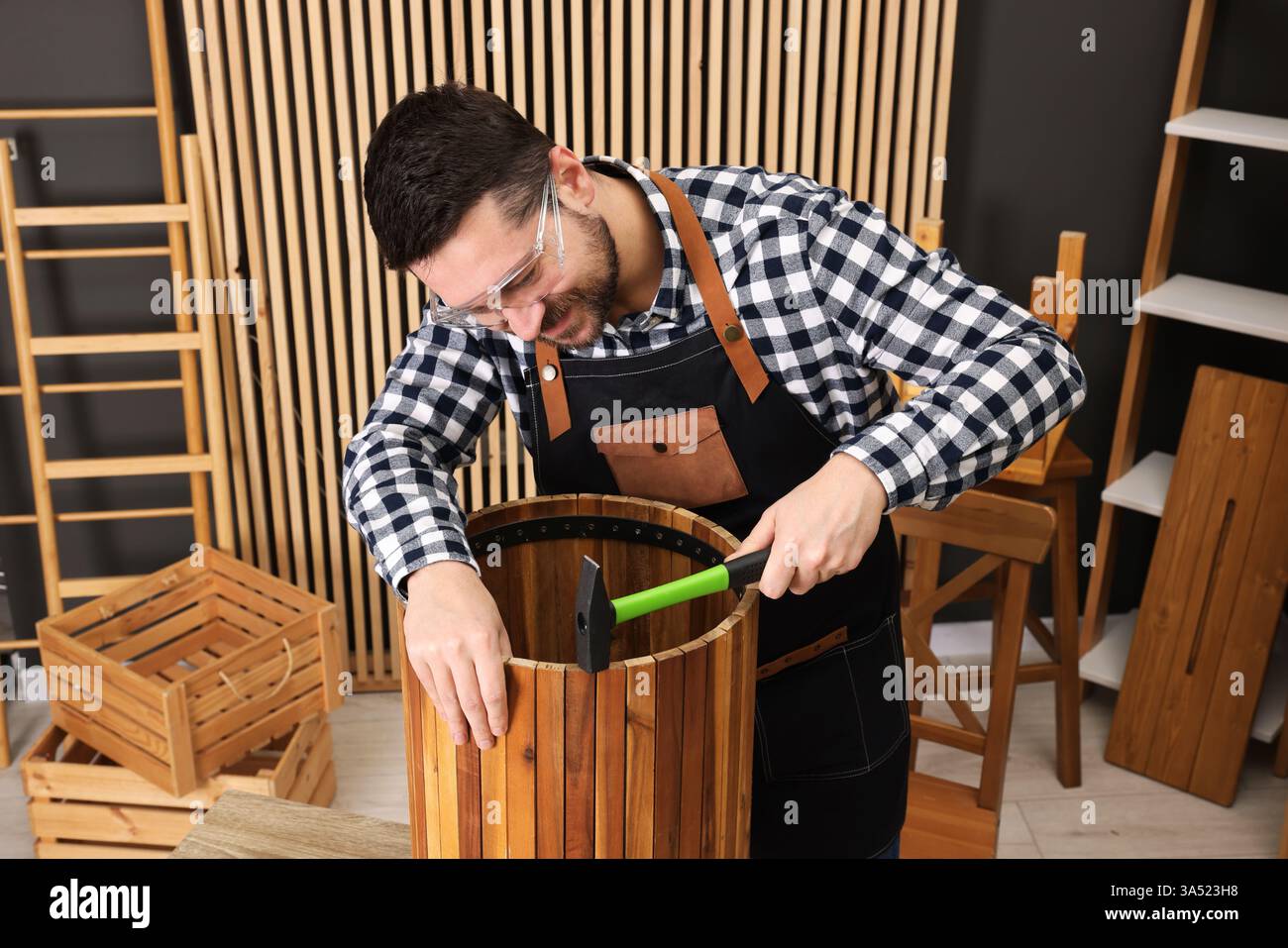 Relaxing hobby. Man repairing wooden trash can with hammer in workshop ...