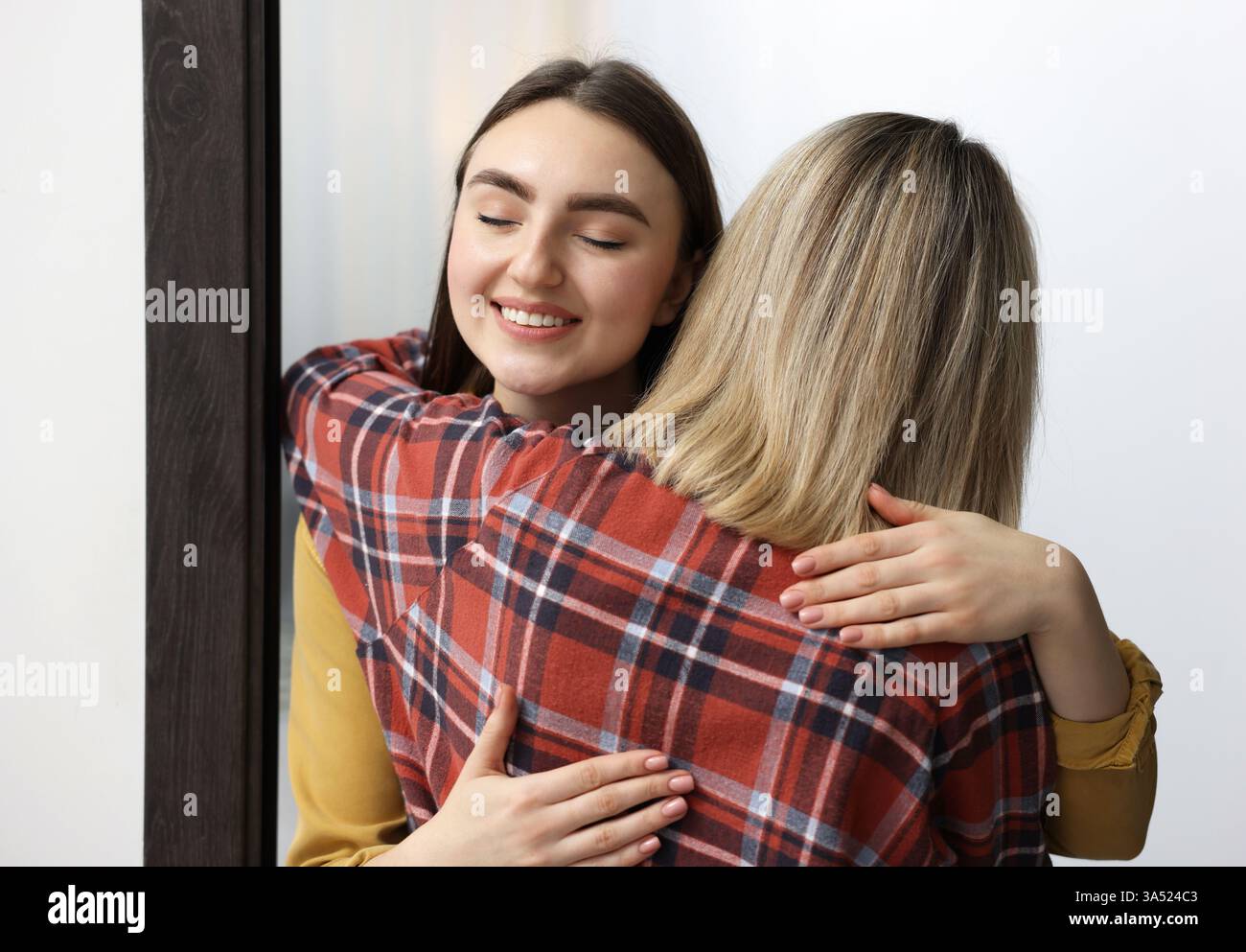 Happy woman welcoming friend to her apartment Stock Photo - Alamy