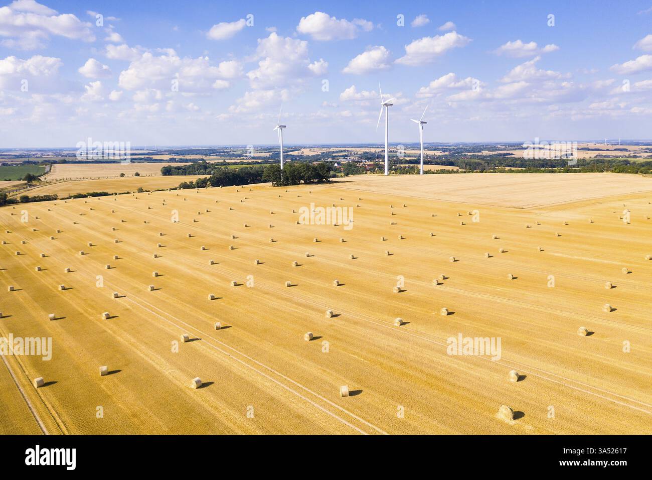 Straw bales on a harvested grain field from above, wind turbines in the ...