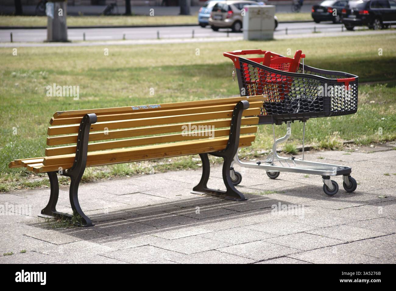 A modern plastic shopping trolley stands next to a park bench in the ...