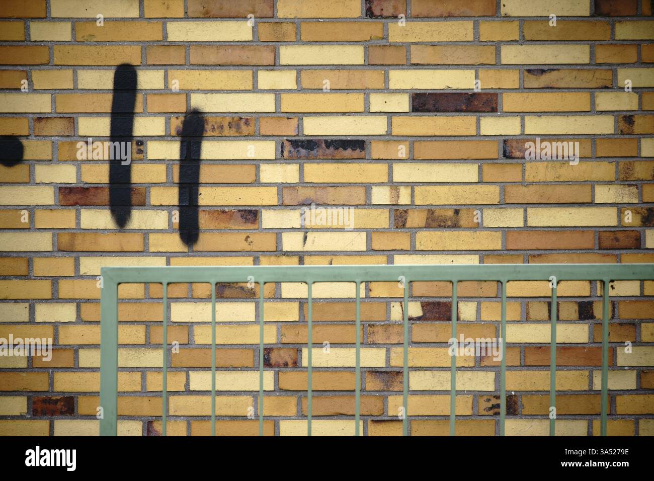 A wall made of old clinker bricks with an angular railing in front of ...