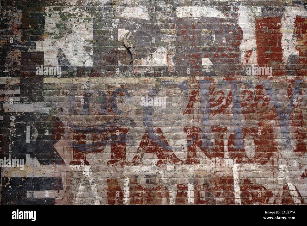 An old brick wall of a ruin and house with faded lettering and layers ...