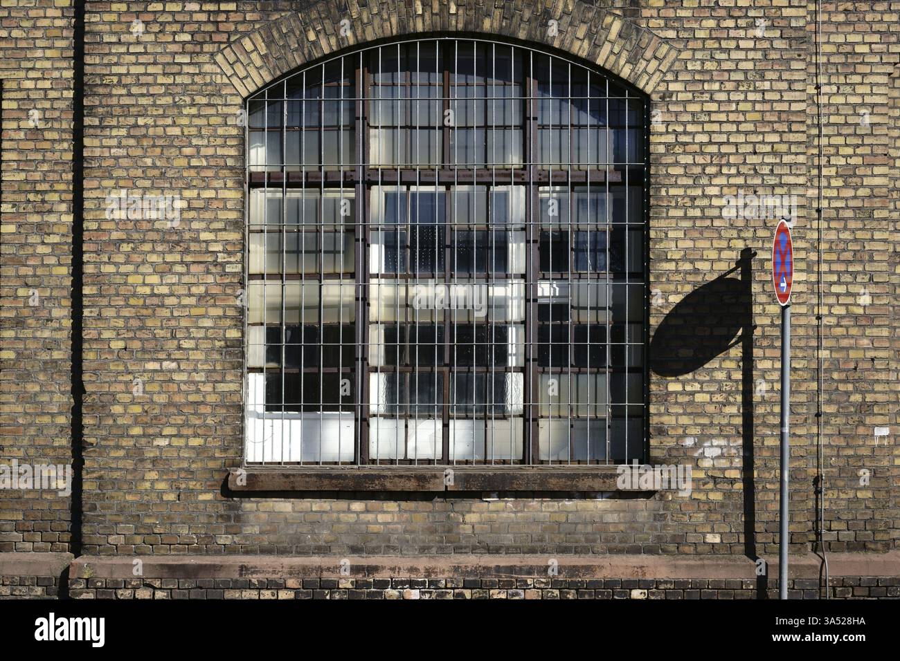 A no stopping sign casts a shadow on the brick wall on the disused ...