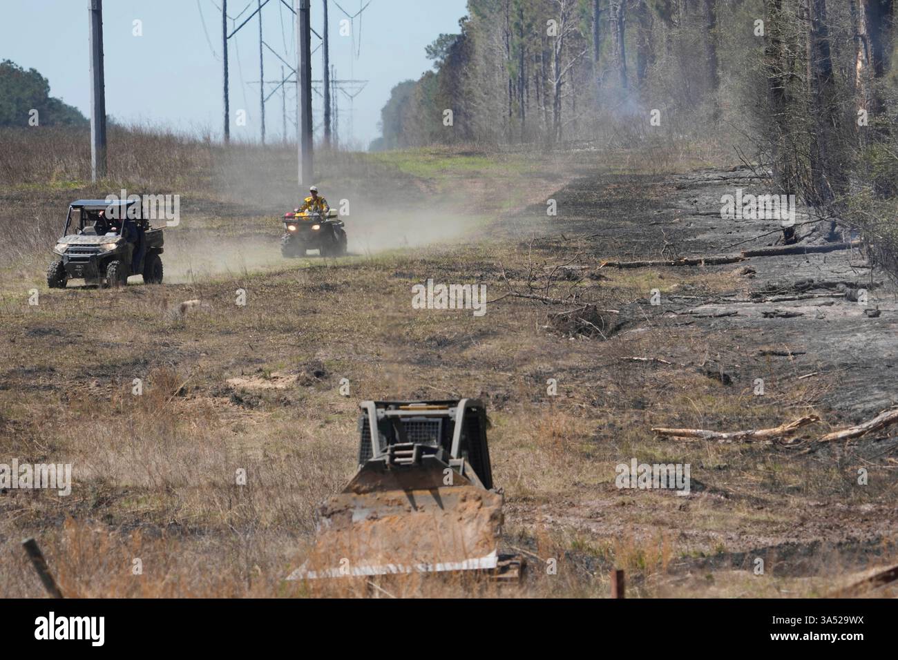Fire crew members drive along a fire line while working to contain the ...