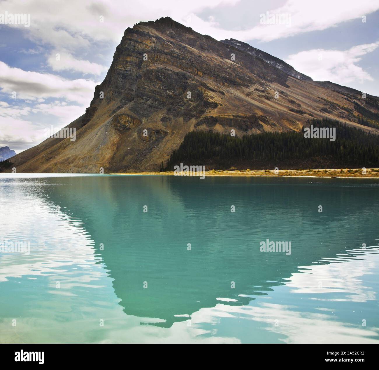 The huge rock of the triangular form is reflected in emerald waters of ...