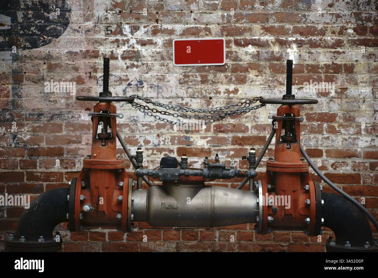 A pumping station stands in front of an old brick wall with faded ...