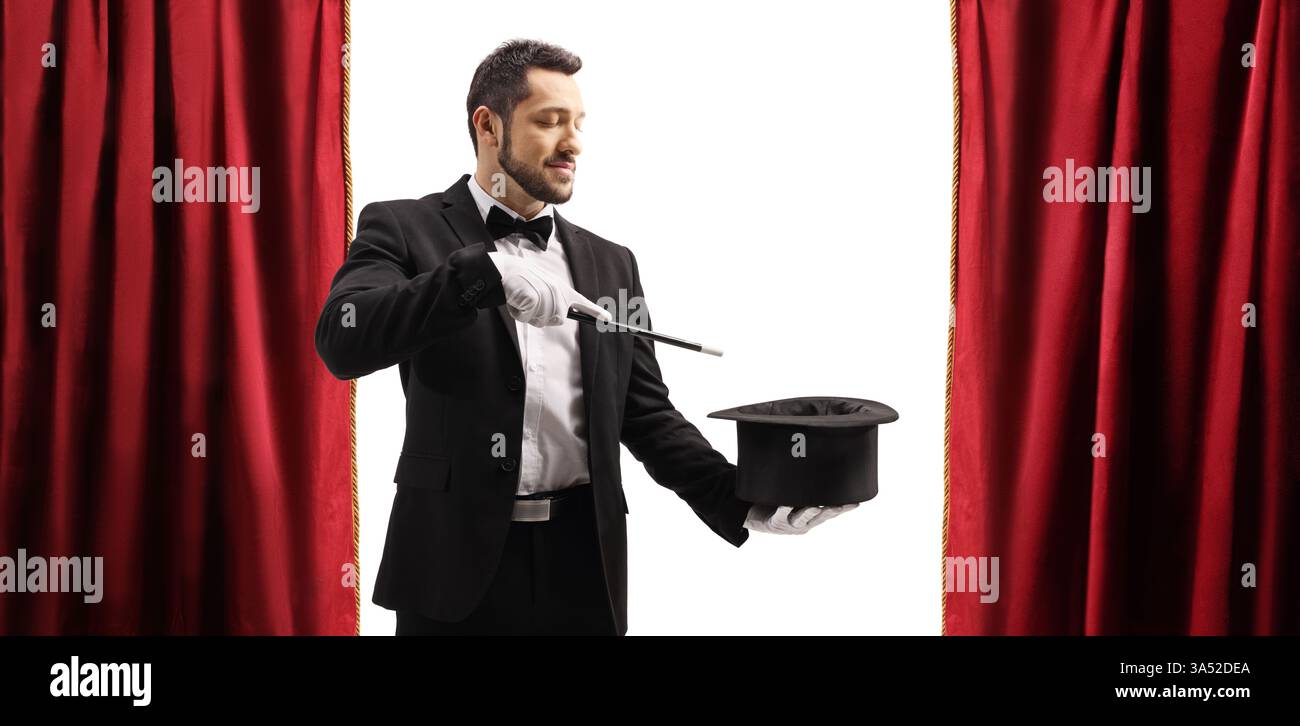 Magician performing a trick with a magic wand and a top hat on stage ...