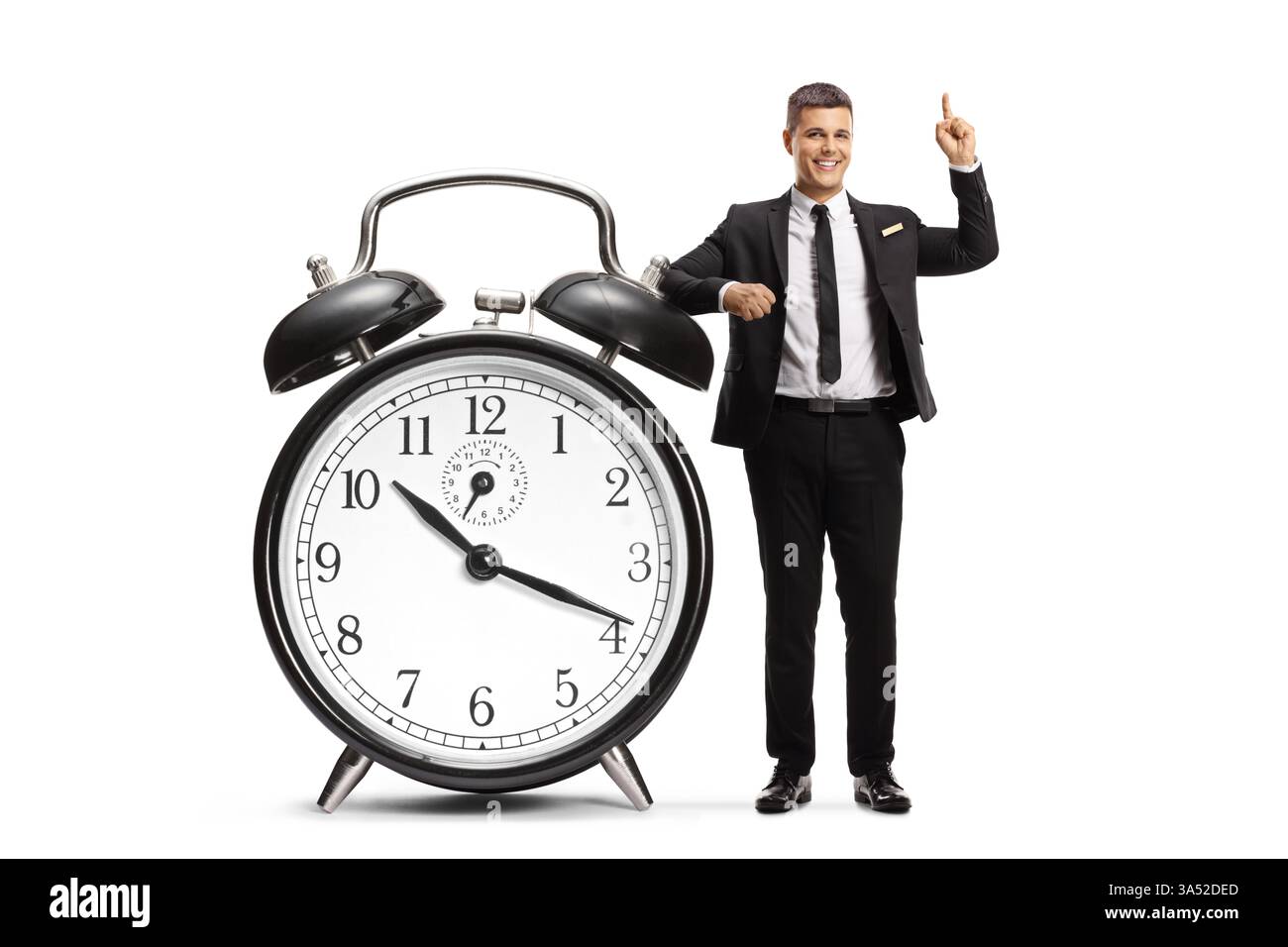 Man in a suit and tie leaning on a big alarm clock and pointing up ...