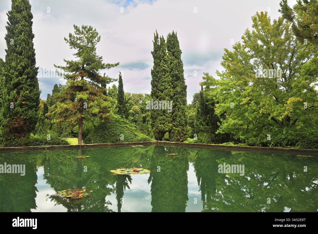 Magnificent Italian park at sunset. Smooth water of a pond reflects ...