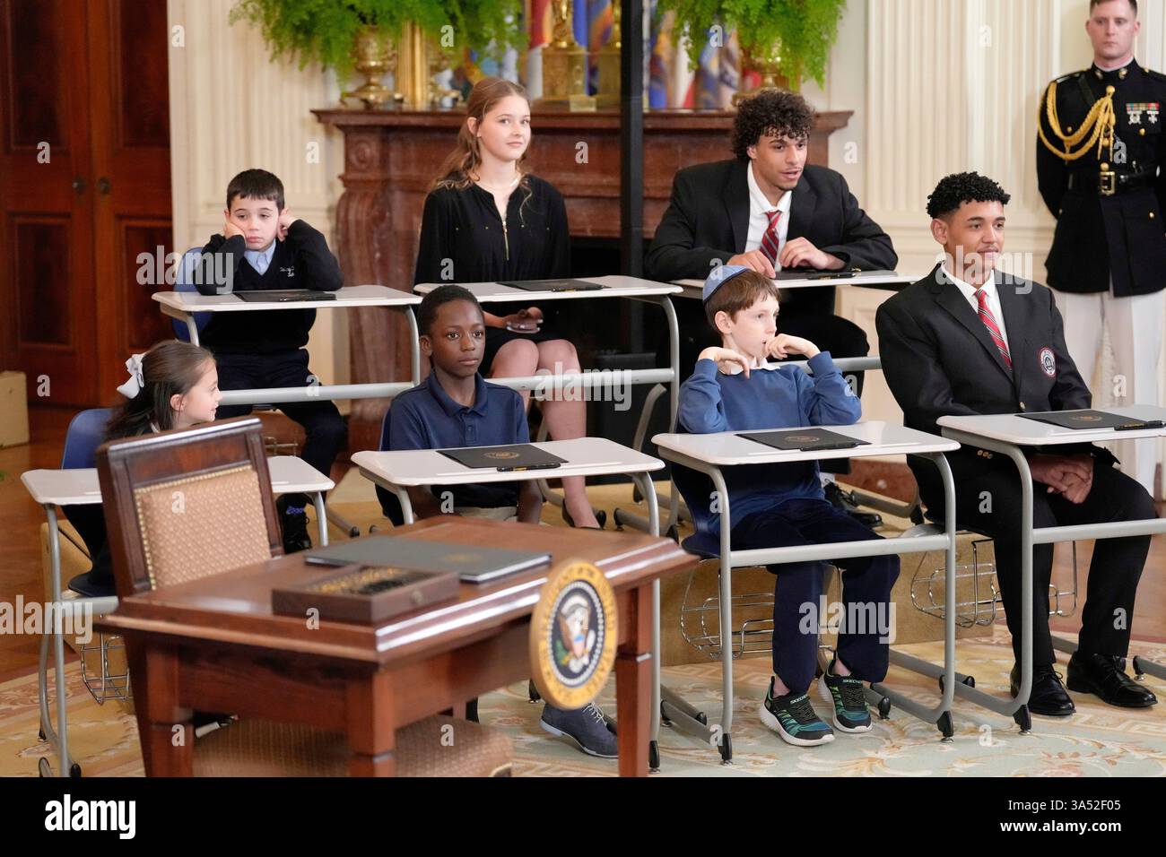 Children sit at desks on stage before President Donald Trump arrives to ...