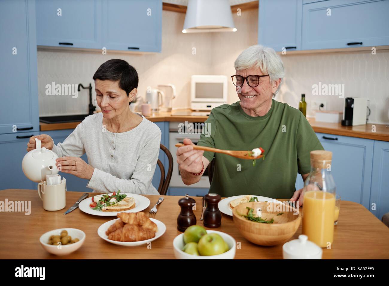 Elderly man and Caucasian woman enjoying breakfast at home, sharing ...