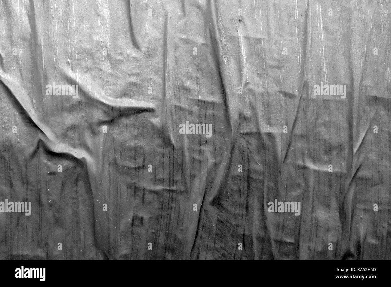 The close-up of wrinkles on a homogeneous black poster on a billboard ...
