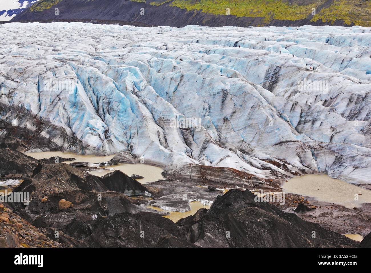 Skaftafell National Park. Blue ice covered ground black volcanic ash ...