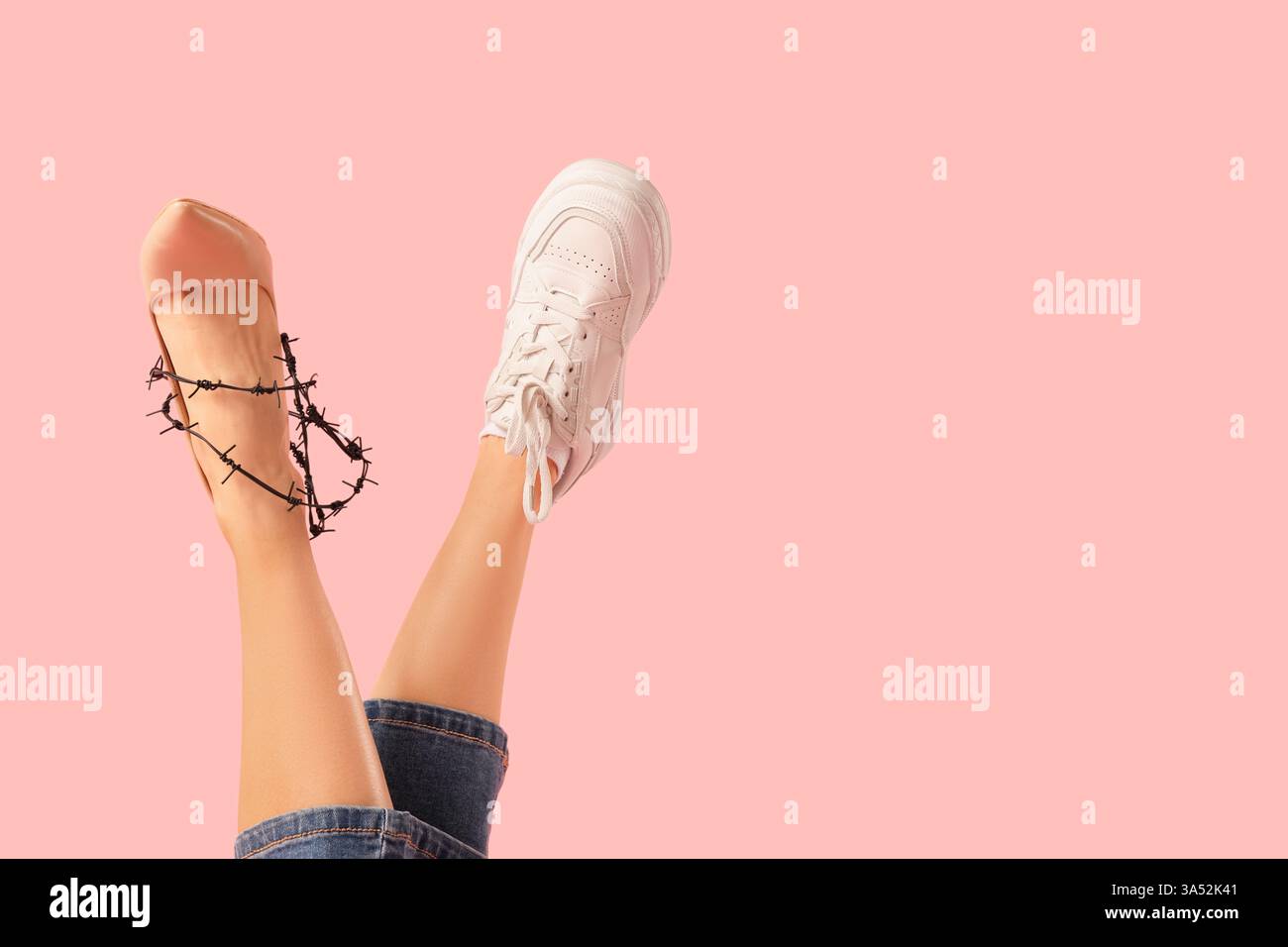 Female legs wearing sneaker and shoe in barbed wire on pink background ...