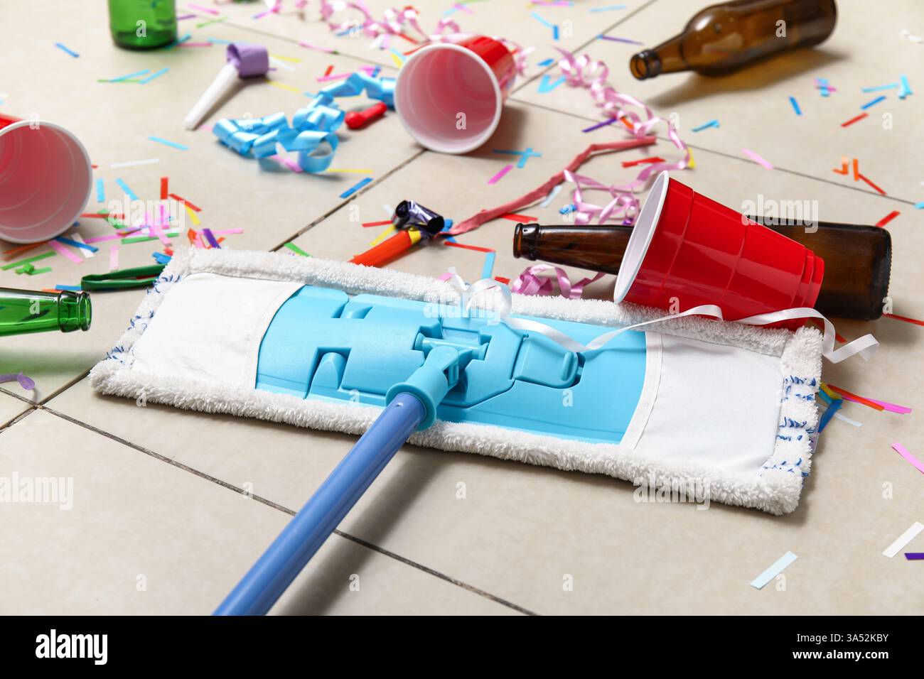 Mop with confetti, cups and bottles on tile floor after party, closeup ...
