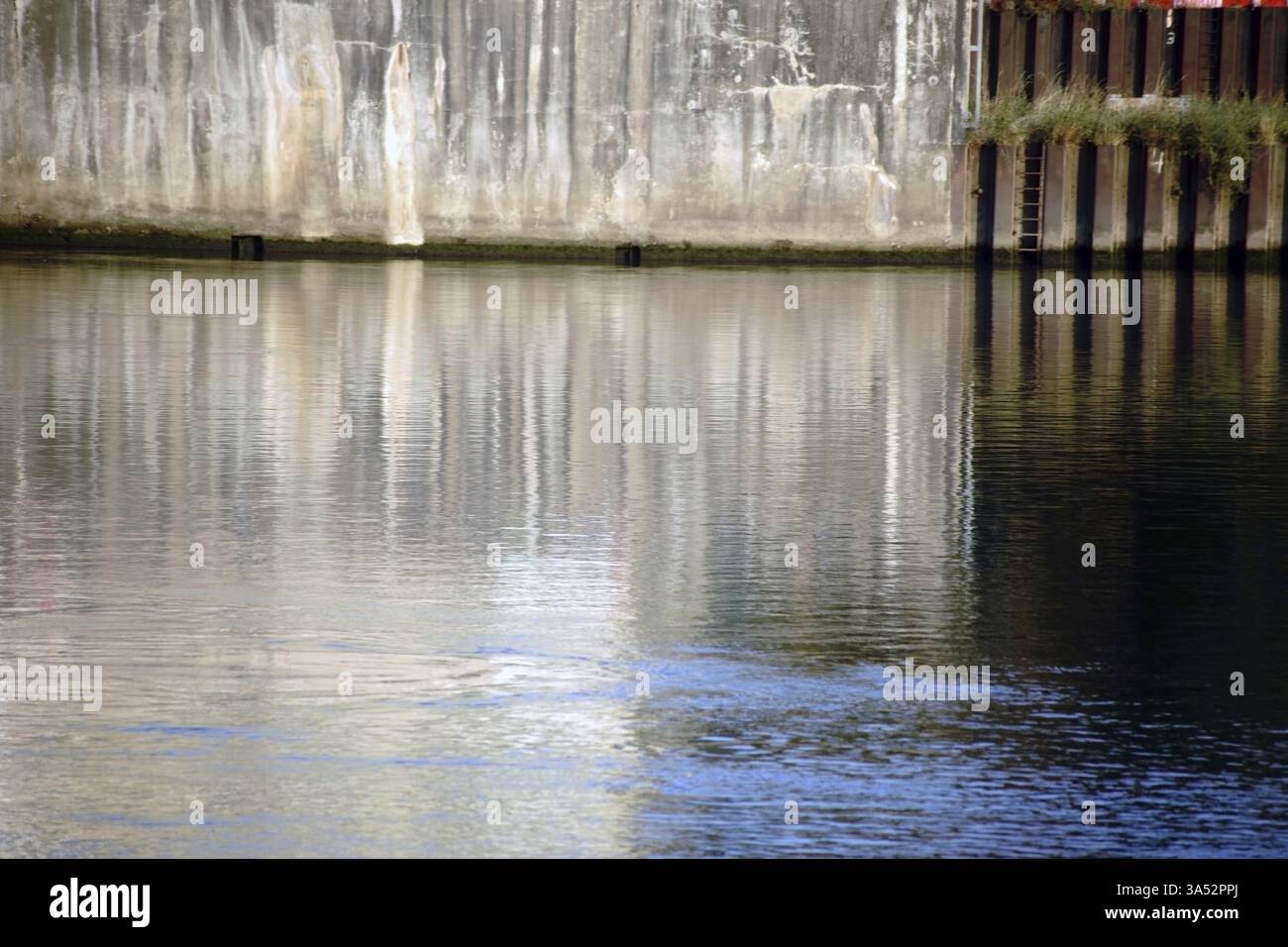 A river boundary or dam wall is reflected on the water surface of a ...
