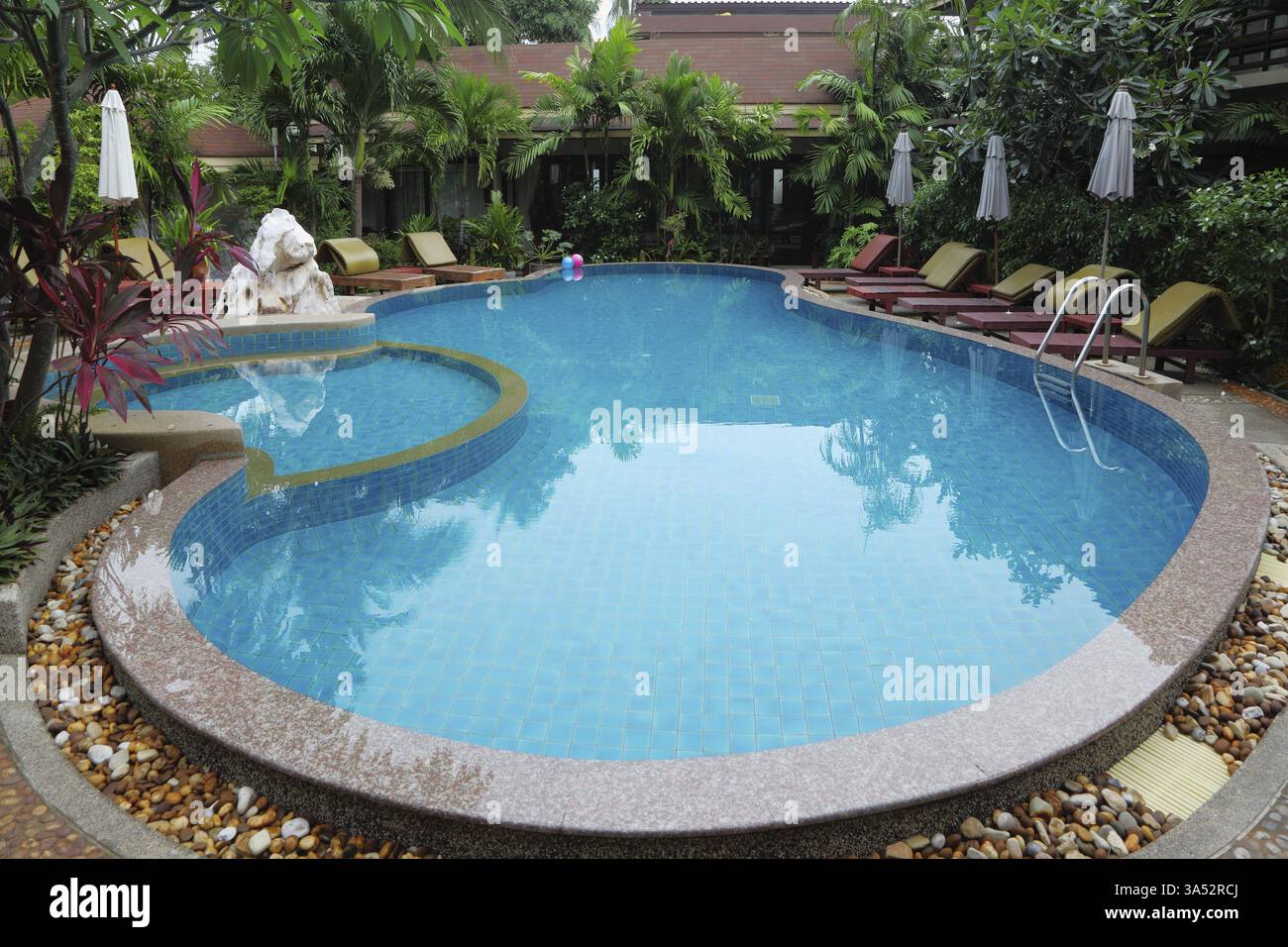 Whimsically curved pool with crystal clear water surrounded by palm ...
