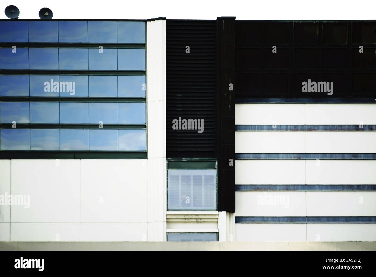 The interlocking facade of a commercial building with cloud reflections ...