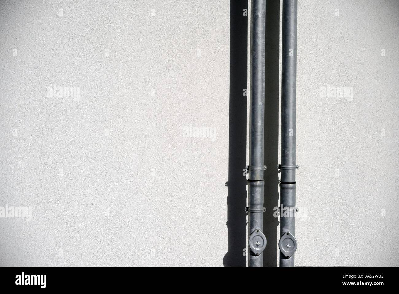 A rainwater pipe casts a shadow on a new exterior plaster wall Stock ...