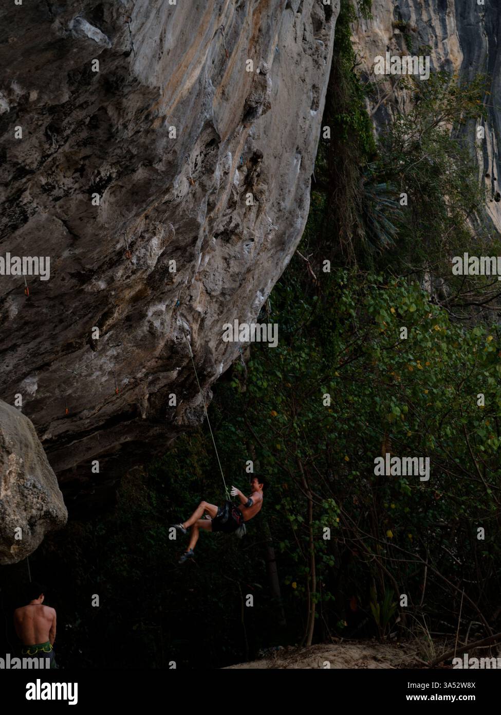 A rock climber dangles from a rope after a challenging ascent on ...