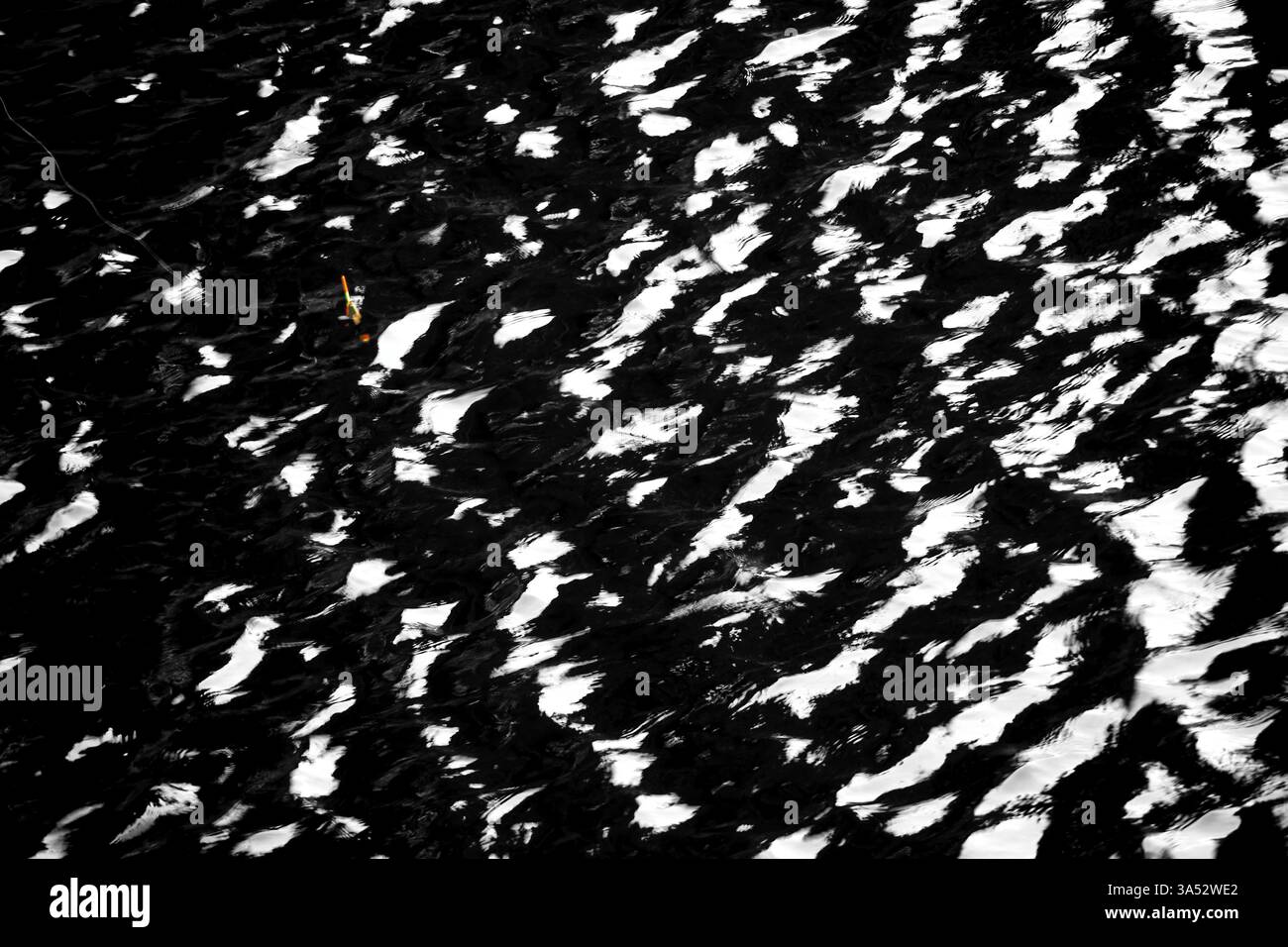 The photograph of a fishing float with signal colour floating on a wavy ...