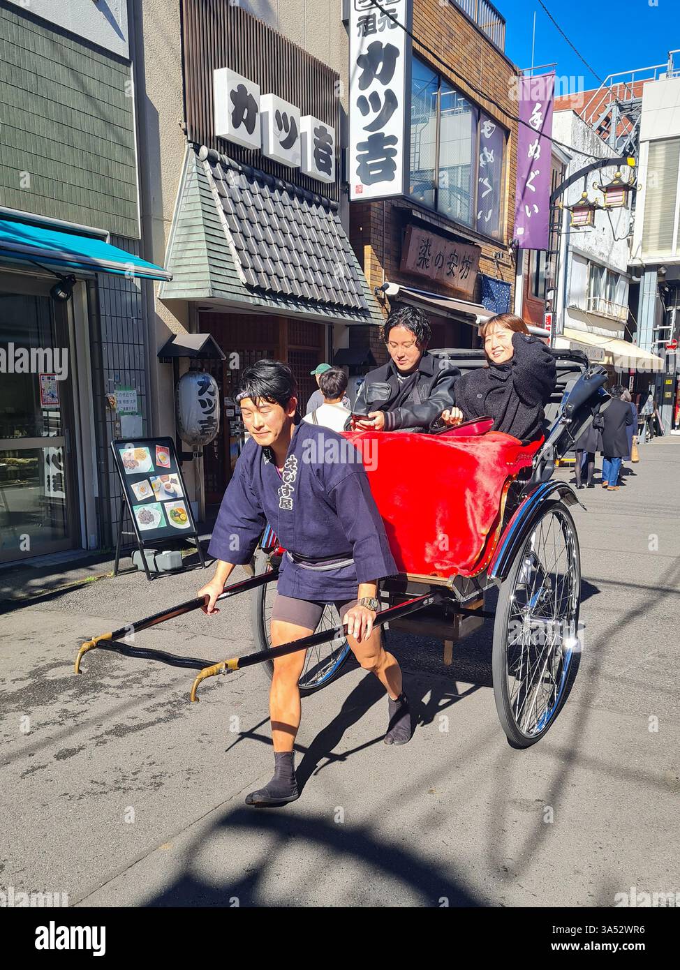 Driver pulling a a rickshaw with customers on board in the Asakusa ...