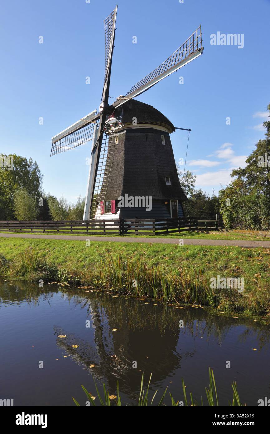 The ancient windmill is reflected in water of a small pond. Clear ...