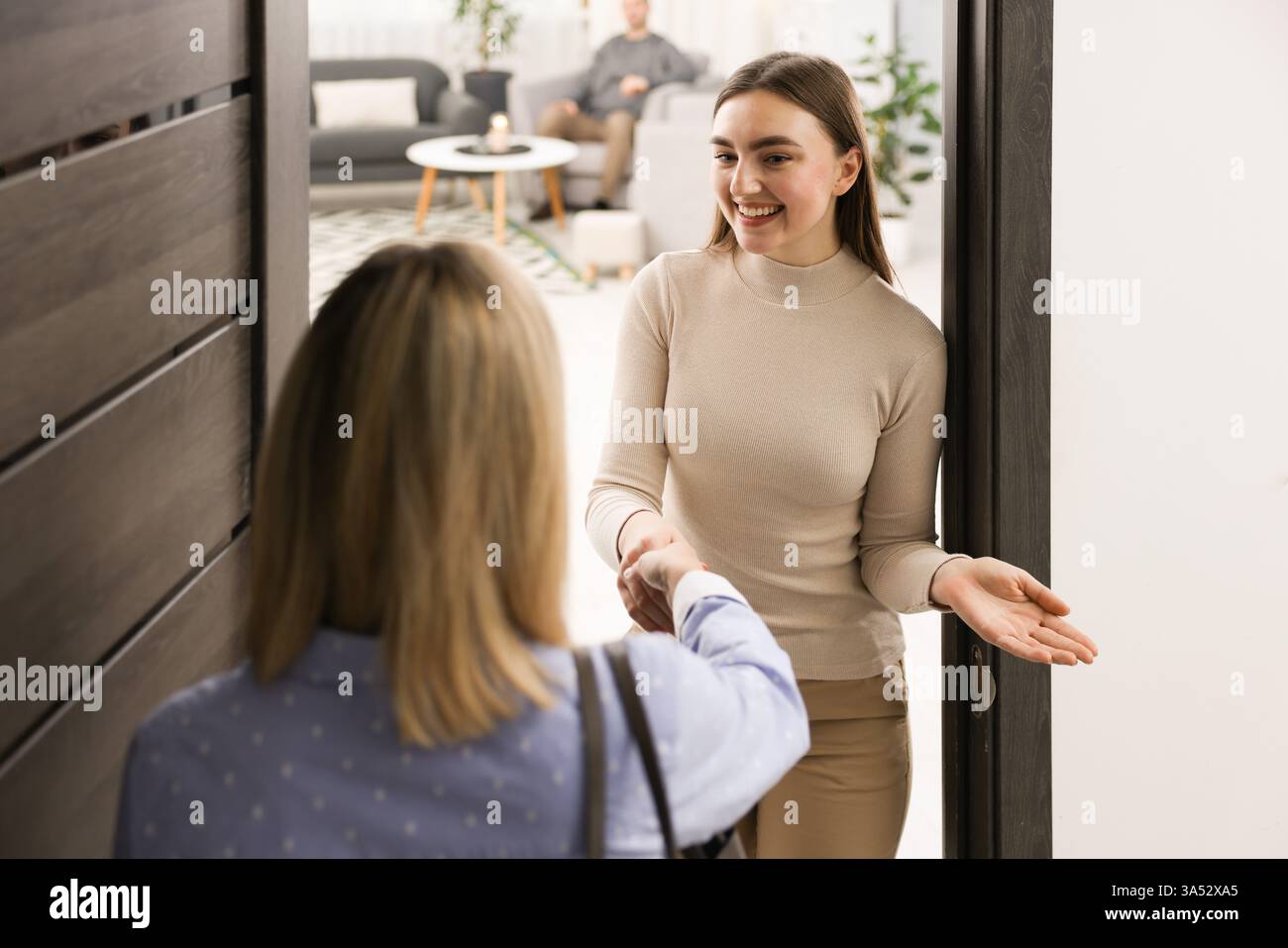 Happy woman greeting neighbor and welcoming her to apartment Stock ...