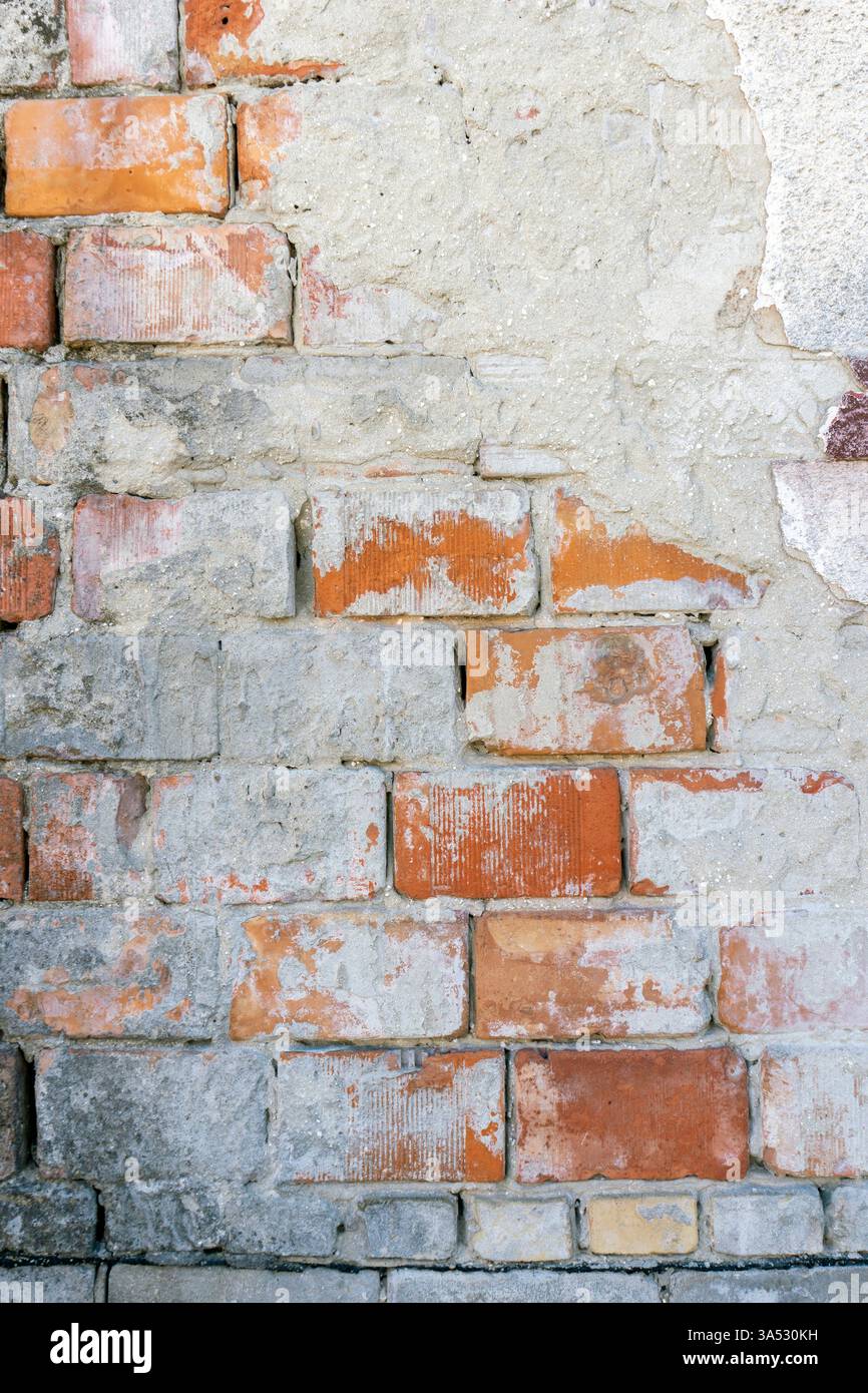 In an urban setting, a weathered brick wall displays various textures ...