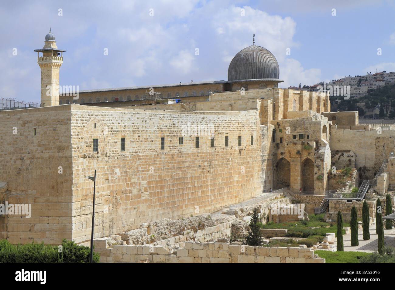 The ancient walls of Jerusalem, lit morning sun. Gray dome of the Al ...