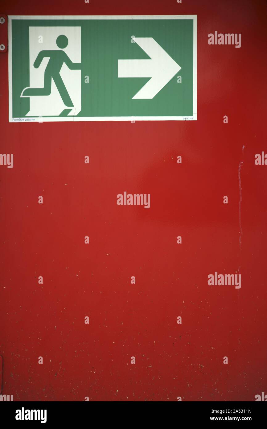 An emergency exit sign and signpost for an escape route in green on a ...