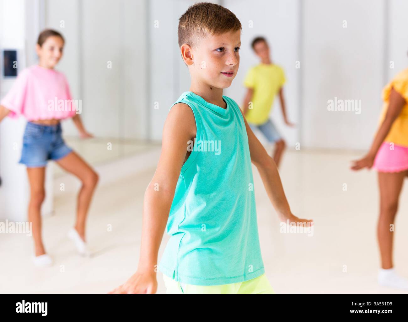 Concentrated tween boy learning charleston during group dance class ...