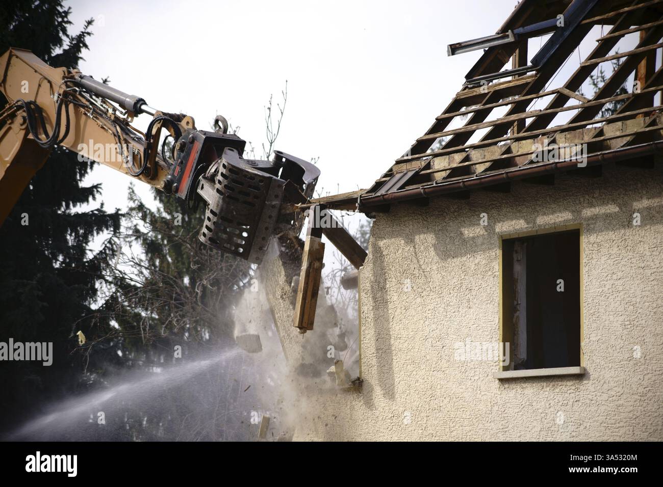 A crane works on the side of a residential building and tears down the ...