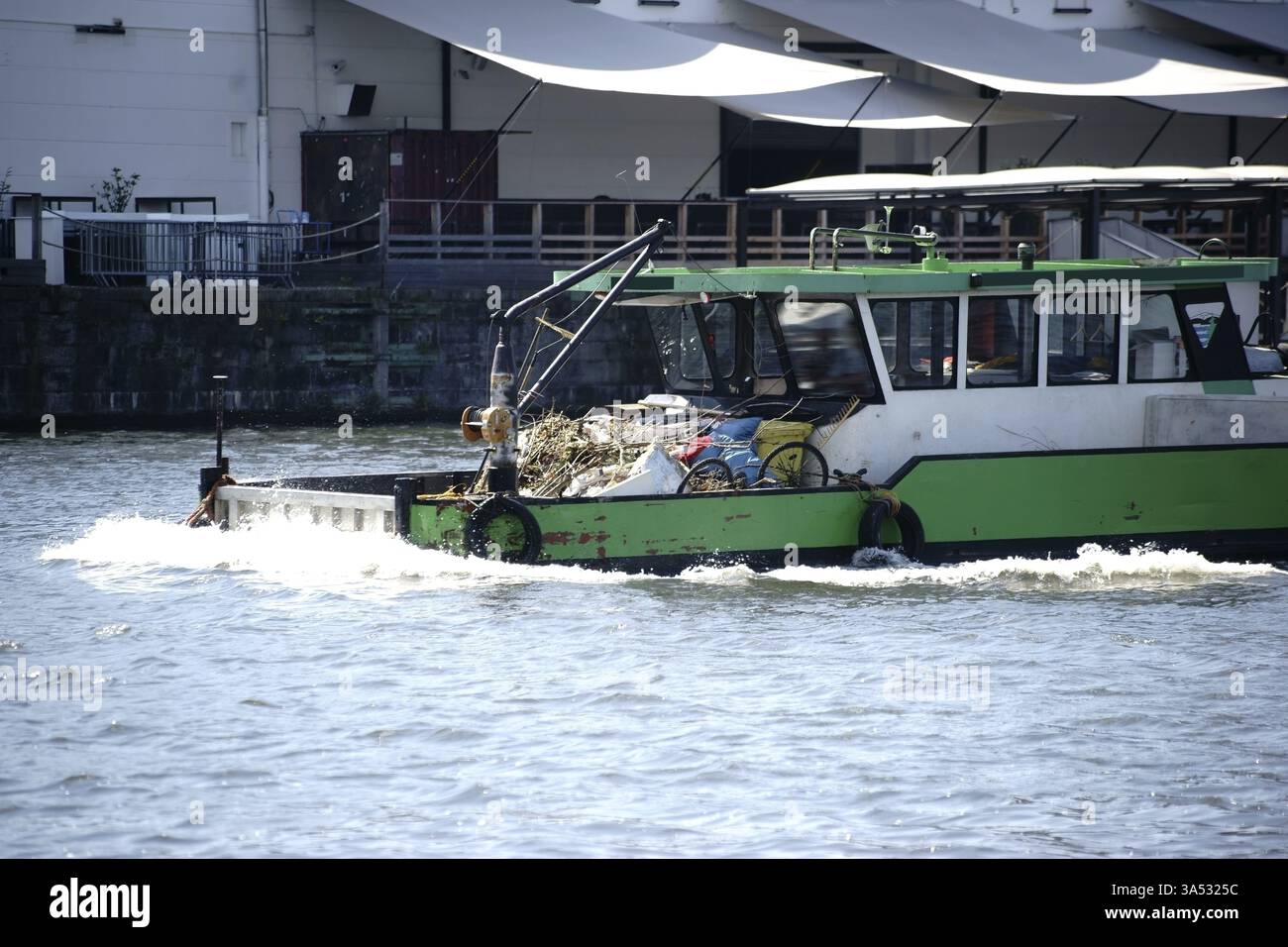 A ship with a loading platform transports rubbish and waste on a river ...