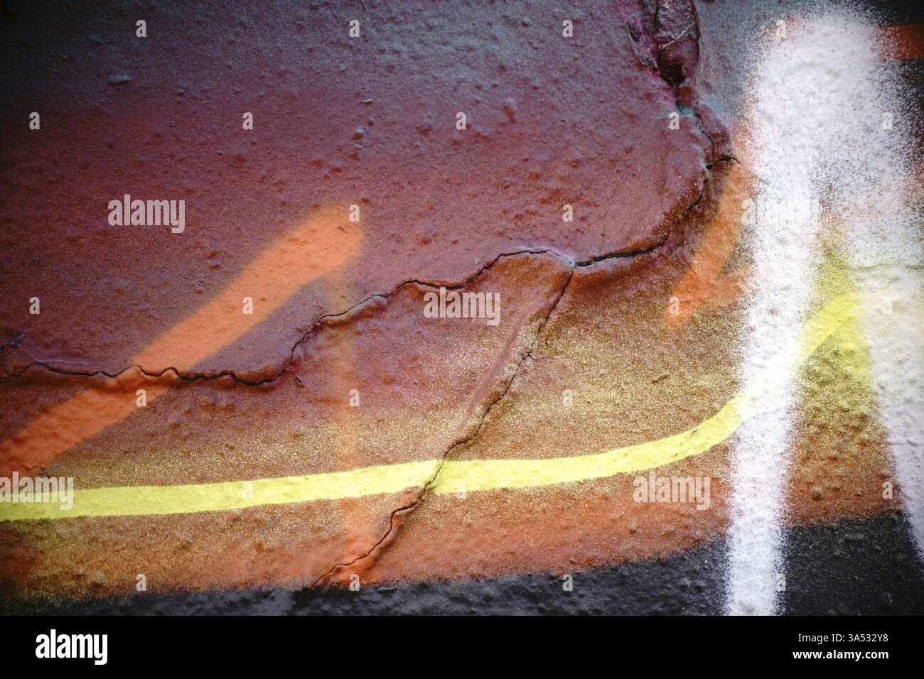 A close-up of a burst layer of coloured paint on the surface of a wall ...