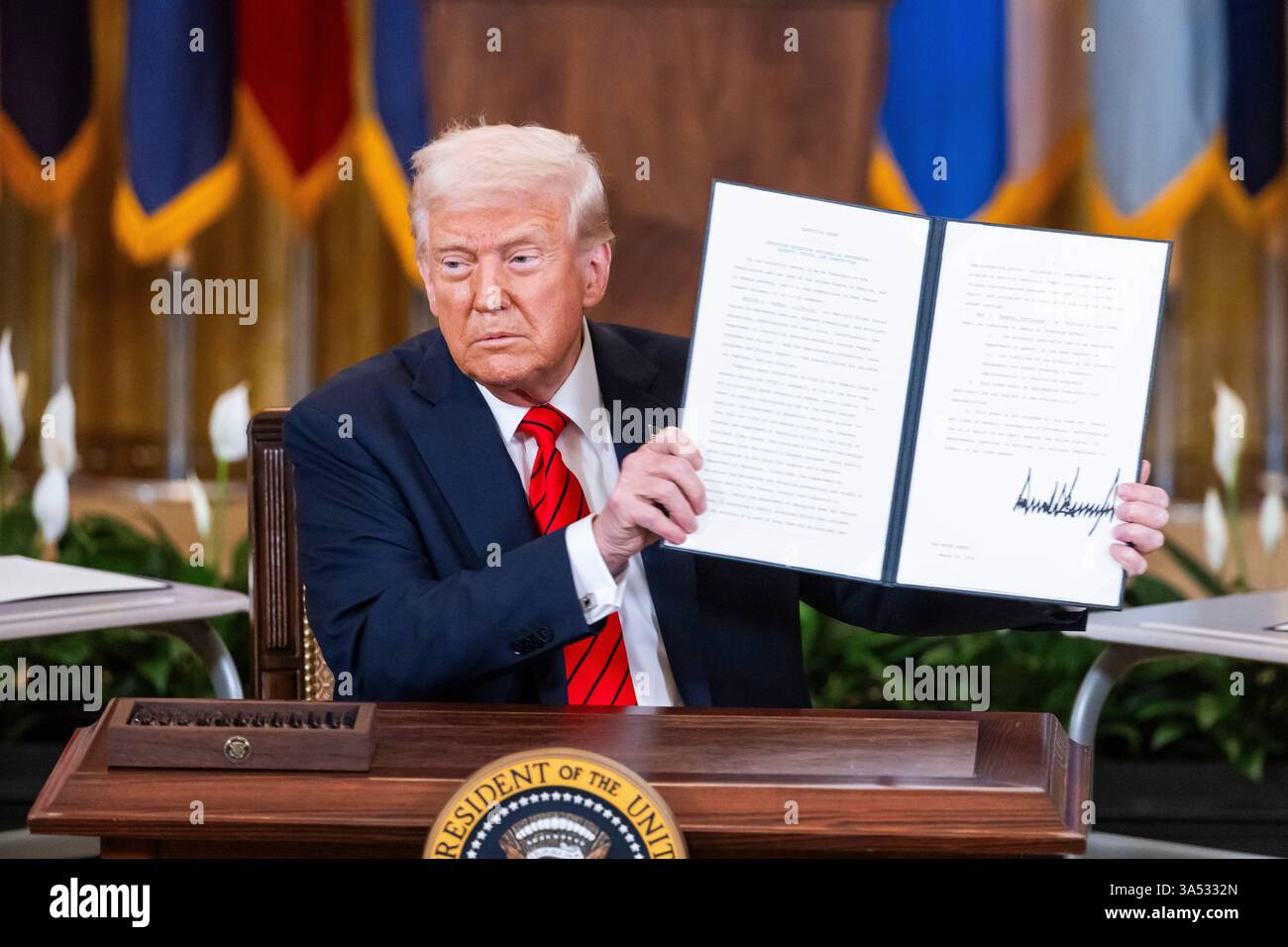 US President Donald Trump shows an executive order he signed aimed at ...