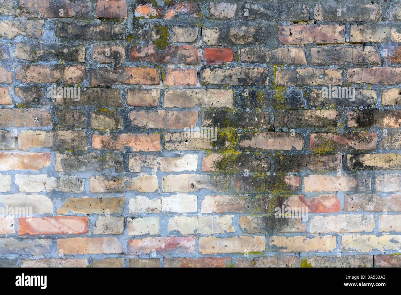 A weathered brick wall exhibits various colors and textures from years ...