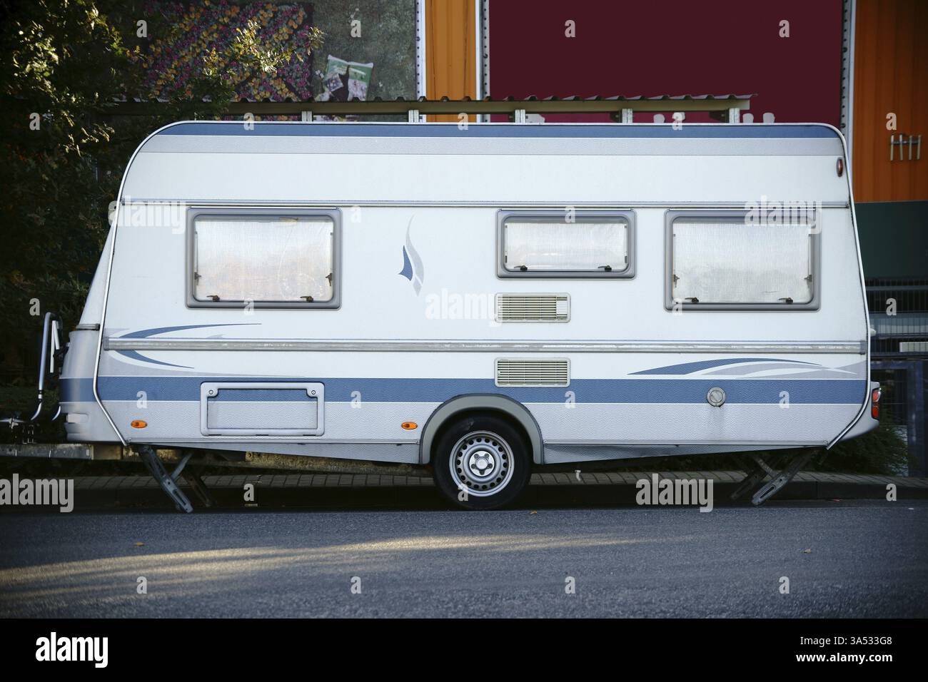 A white modern caravan and camping trailer made of sheet metal is ...