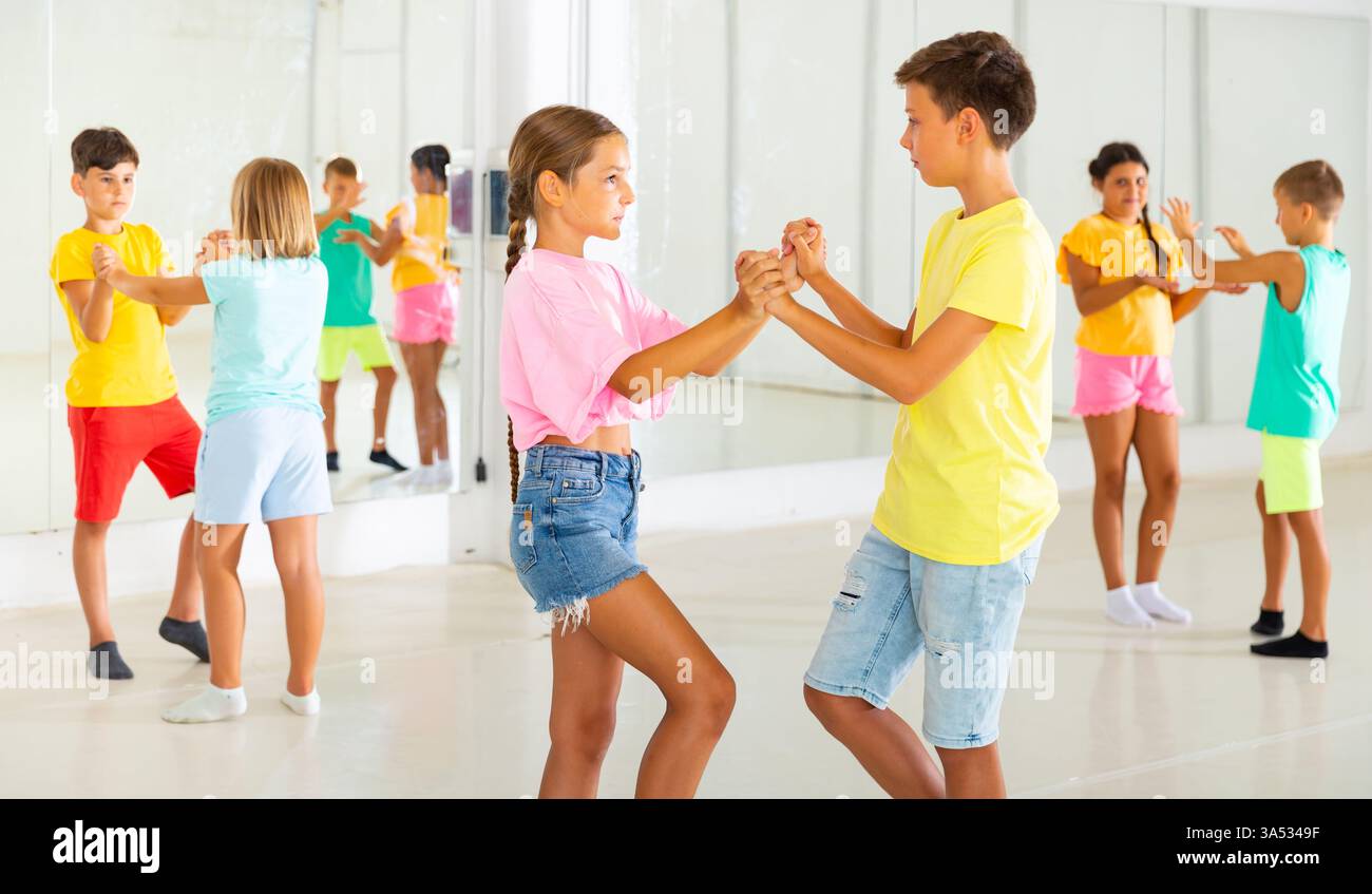 Sporty preteen children learning to dance vigorous jive in pairs Stock ...
