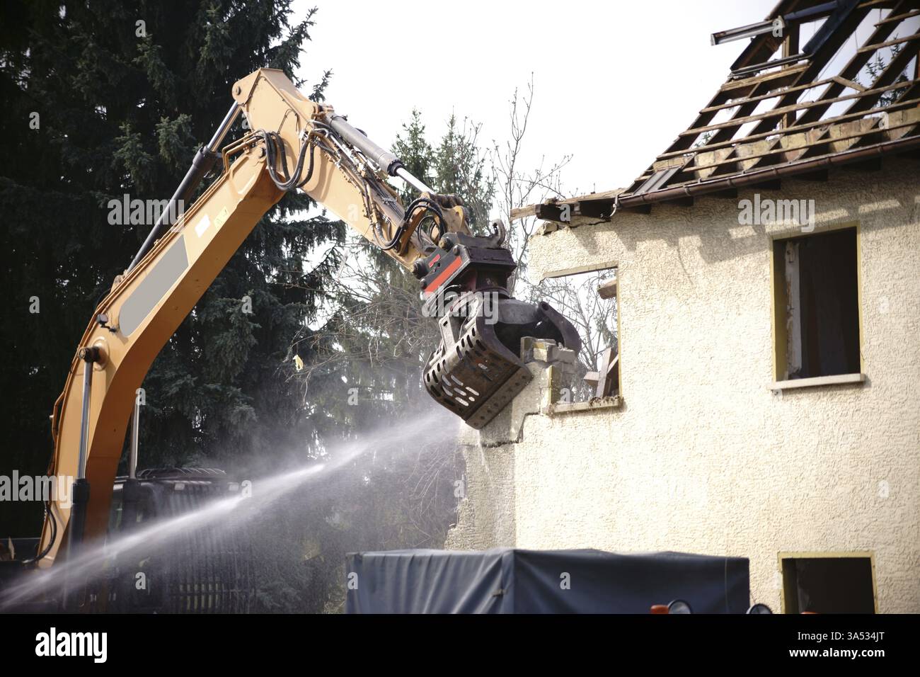 A crane is working on the side of a residential building, tearing down ...