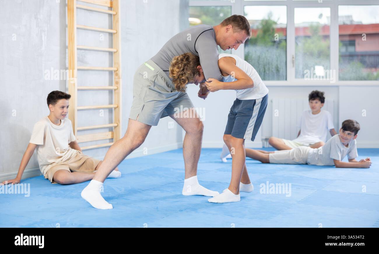 Trainer teaching kids basics of fighting for self-defense in gym Stock Photo - Alamy