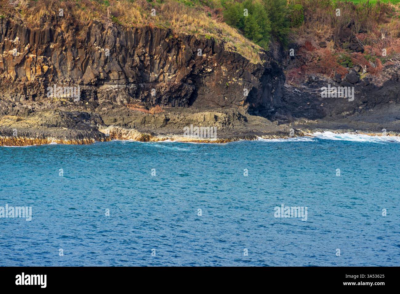 Small cliff on a beach with ocean water on the Island of Kauai of ...