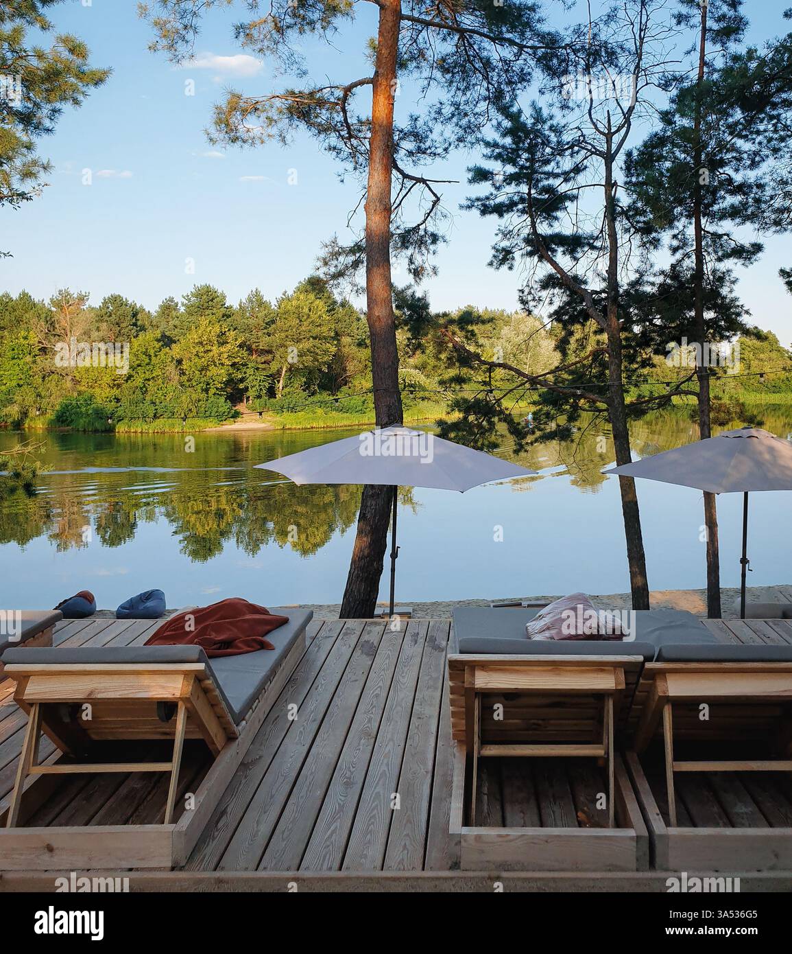 Beach on a forest river: wooden boardwalk with wooden deckchairs and ...