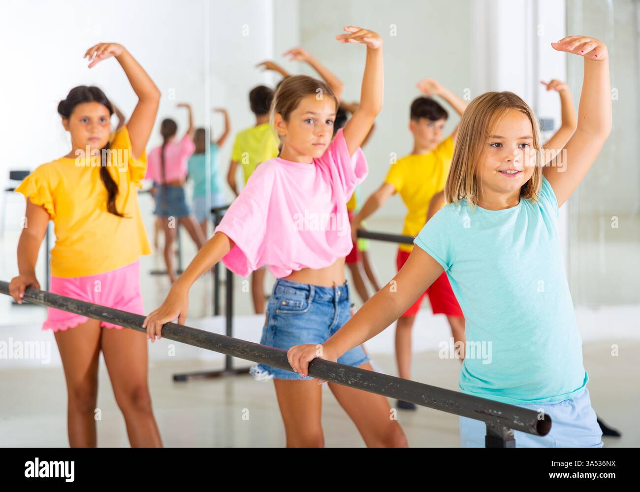 Children standing along ballet bar in dance studio during dance class ...