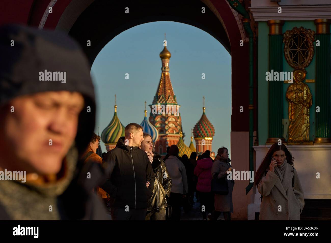 People walk from Red Square through the Resurrection Gate during sunset ...