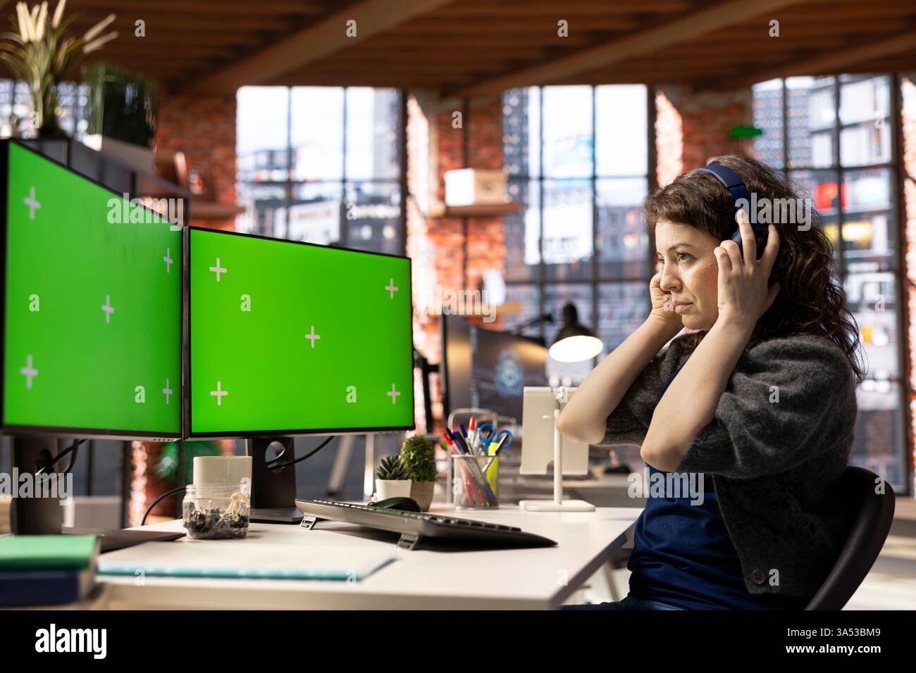 Female employee uses green screen mockup and headset to finish tasks in ...