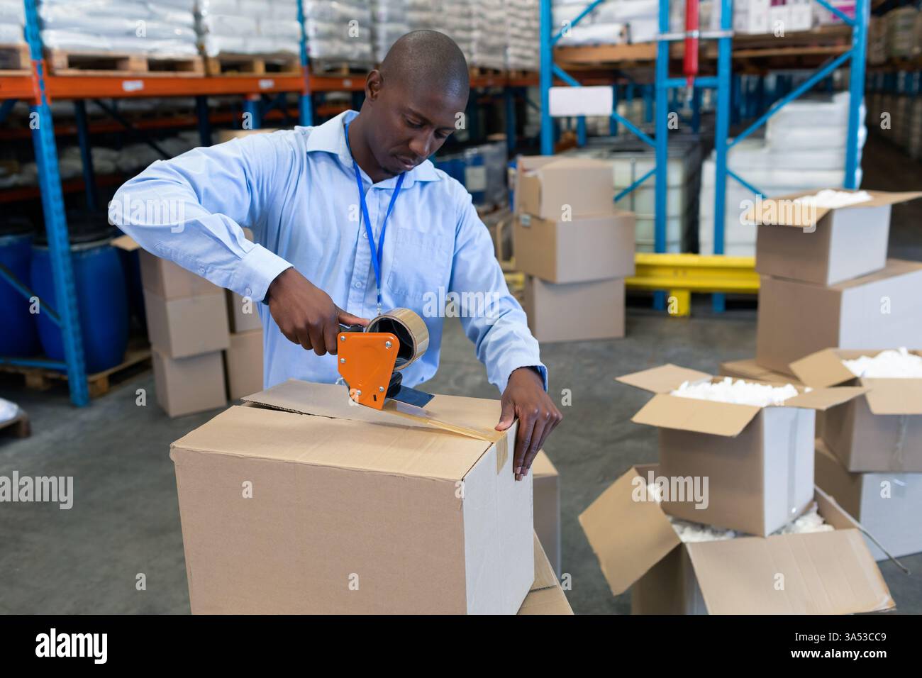 Warehouse worker sealing cardboard box with tape dispenser, focusing on ...