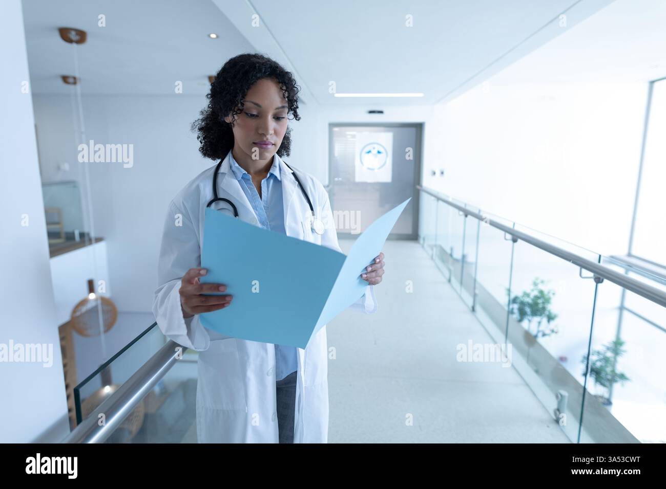 Doctor reviewing patient file in hospital corridor, focused on ...