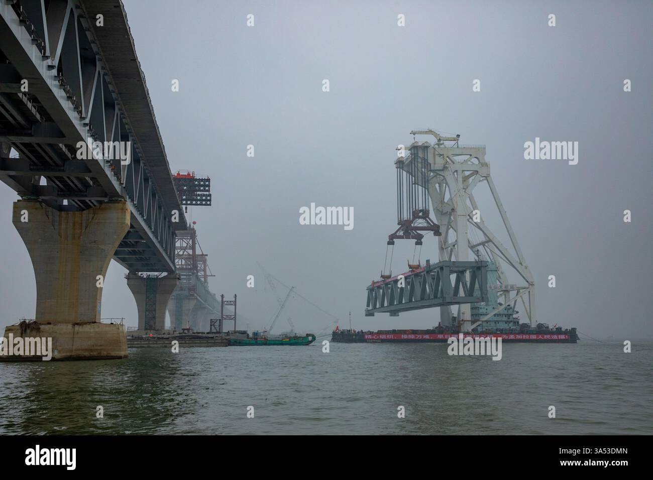 A giant crane transports the final span for installation on pillars 12 ...
