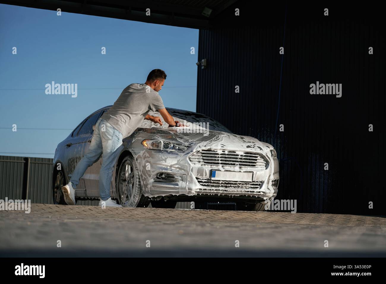 Foam is being washed, automobile is in soap. Man is with his car ...